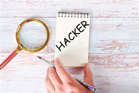 Hacker Word On A Notebook In A Man S Hand With A Pencil And A Magnifying Glass Next To It Stock
