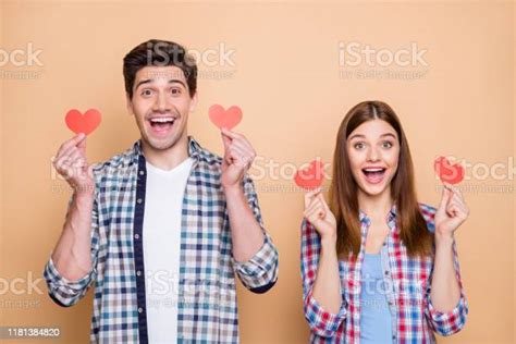 캐주얼 쾌활한 빨간 머리 세련된 귀여운 매력적인 아름다운 부부의 사진은 베이지 색 파스텔 배경을 통해 고립 된 새로운 작은 빨간 엽서를 받은 것에 대해 기뻐합니다 2명에