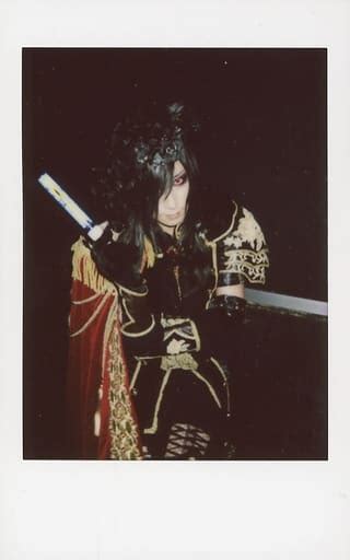 駿河屋 D Asagi 膝上・衣装黒・赤・金・右向き・右手ペンライト・左手曲げ・目線正面・背景黒 生チェキ（男性生写真）