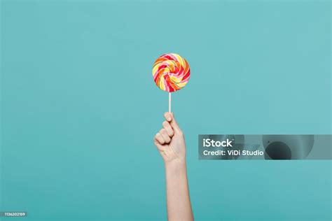 가까이 여자 손에 들고 다채로운 라운드 롤리팝 파란색 청록색 벽 배경에 고립 적절 한 영양 또는 과자 디저트 패스트 푸드 다이어트 아침 개념입니다 광고 공간을 복사 합니다