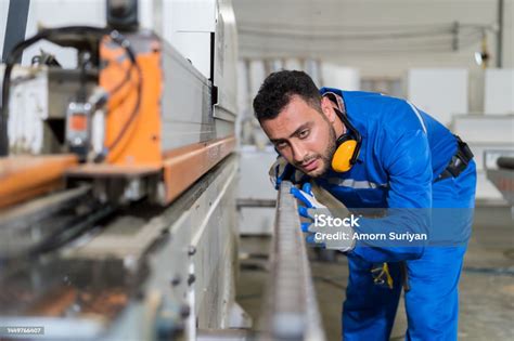 산업 공장에서 컨베이어 벨트 기계를 확인하는 남성 엔지니어 노동자 남성 기술자는 공장에서 안전 장갑과 균일 한 작업 유지 보수 기계를 착용합니다 수리에 대한 스톡 사진 및