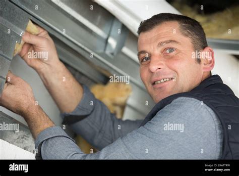 Man Inserting Insulation Behind A Metal Framework Stock Photo Alamy