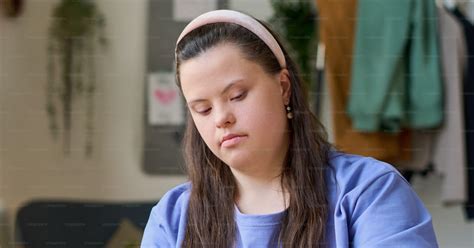 다운증후군 여학생이 온라인 수업 중 집에서 노트북 앞 책상에 앉아 메모장에 메모하는 모습 사진 Unsplash의 고집 이미지