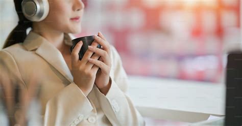 커피 컵을 들고 음악을 들으며 편안한 기분을 느끼는 사업가 사진 Unsplash의 헤드폰 이미지