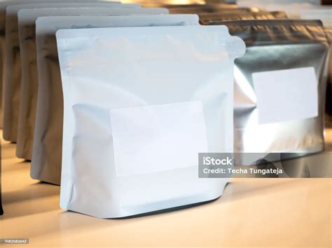 현대적인 흰색과 은색 호일 가방 커피 원두 포장에 빈 흰색 라벨을 닫습니다 모형 템플릿 스티커 레이블입니다 선반에 진열된 커피