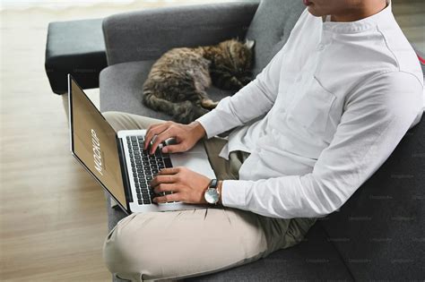 집 거실의 소파에 앉아 노트북으로 작업하는 남자의 자른 장면 사진 Unsplash의 입력 이미지