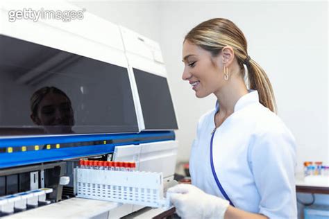 Lab Tech Loading Samples Into A Chemistry Analyzer Female Lab Tech Loading Specimen For