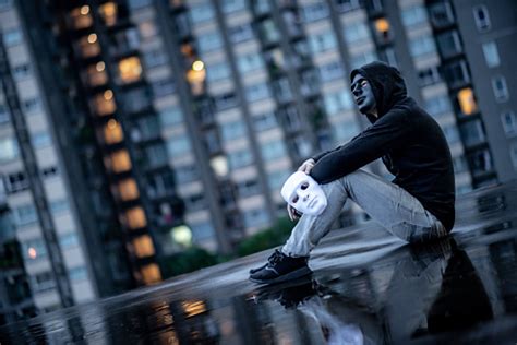 버려진된 건물의 옥상에서 비에 앉아 흰 마스크를 들고 검은 마스크와 미스 테리 까마귀 남자의 반사 양극성 장애 또는 주요 우울증 장애입니다 우울증 개념 가린 얼굴에 대한