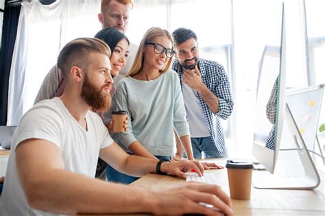 성공적인 프로젝트를 논의 작업 및 백그라운드에 앉아 동료와 함께 사무실 책상에 앉아 있는 동안 통신 젊은 명랑 사업 사람들의 그룹입니다 가리키기에 대한 스톡 사진 및 기타