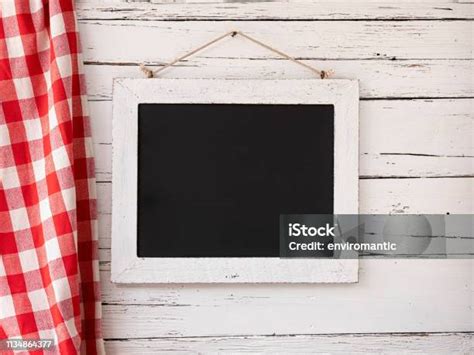 오래 된 흰색 풍 화 된 티크 나무 액자 칠판은 보드의 왼쪽에 매달려 빨간색 체크 깅 엄 소재 식탁보와 함께 오래 된 흰색 풍 화 티크 나무 패널 벽 배경에 대 한 오래 된