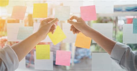 동료와 함께 유리 벽에 스티커 메모를 읽는 창의적인 사업가들은 포스트잇 노트를 사용하여 아이디어 토론과 팀워크 브레인스토밍 개념을 공유합니다 근접 촬영 사진