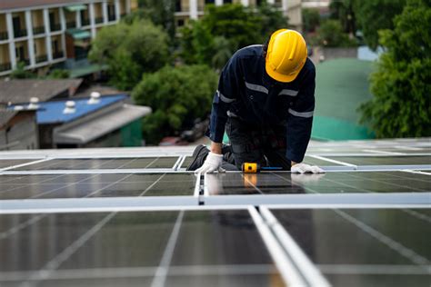 공장 옥상에 설치된 전자기기로 태양전지나 태양전지를 점검하는 남성 엔지니어 기술자 작업자가 시스템을 수리하거나 검사합니다 산업용 재생 에너지 개념 검사 보기에 대한 스톡