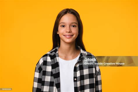 노란 배경에서 카메라를 바라보는 격자 무늬 셔츠를 입은 쾌활한 미소 짓는 젊은 소녀 여학생 백인 십대 소녀 컷 아웃 초상화