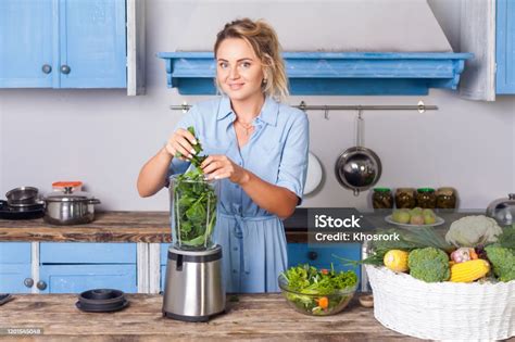 아침 식사 야채 요리 샐러드를 만들기 위해 건강한 스무디를 만들기 위해 믹서기에 재료를 넣는 행복한 여성 부엌에 대한 스톡 사진