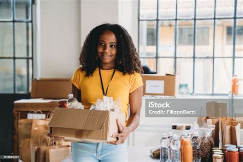 푸드 뱅크에서 음식과 음료의 골판지 상자를 들고 혼합 인종 자원 봉사 여성의 초상화 비영리법인에 대한 스톡 사진 및 기타 이미지 비영리법인 푸드뱅크 자원봉사 Istock