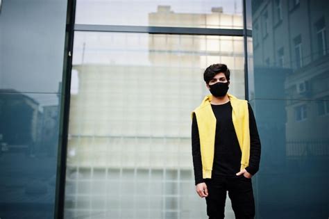 세련된 노란색 운동복을 입은 도시의 젊은 힙스터 인도 남자 멋진 남아시아 남자는 후드티를 입고 검은 얼굴은 뉴 노멀 동안 마스크를 보호합니다 무료 사진