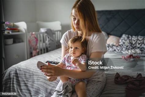 그녀의 어머니가 옷을 갈아 입고있는 동안 집에서 침대에 앉아있는 한 작은 백인 소녀 유아는 복사 공간을 자라는 실제 사람들 12 17 개월에 대한 스톡 사진 및 기타 이미지