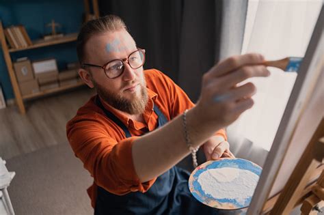 집에서 캔버스에 그림을 그리는 젊은 아프리카 남자는 진지한 표정으로 긴장을 풀었다 카메라를 바라보는 단순하고 자연스러운 모습 35 39세에 대한 스톡 사진 및 기타 이미지