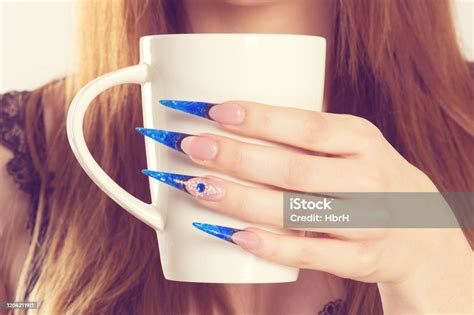 매니큐어 현대 스타일 새로운 트렌드 블루 스틸레토 매니큐어 뜨거운 음료 차 커피와 흰색 컵을 들고 아름다움 손 세련된 다채로운