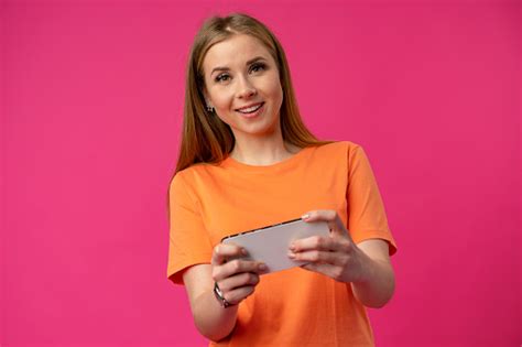 행복한 매력적인 여자는 분홍색 배경에 스마트 폰에 비디오 게임을 재생 Brand Name Smart Phone에 대한 스톡 사진 및 기타 이미지 Brand Name