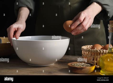 Making Bread Woman Adding Egg Into Dough At Wooden Table On Dark Background Closeup Stock