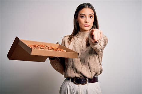 젊은 아름 다운 갈색 머리 여자 들고 상자 위에 흰색 배경 카메라와 당신에 게 손가락으로 가리키는 손 기호 앞에서 긍정적이 고 자신감 제스처 갈색 머리에 대한 스톡 사진 및