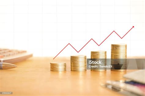 사무실 책상 위에 황금 돈 동전 더미가 있고 그래프와 빨간색 위쪽 화살표가 있습니다 비즈니스 및 금융 개념 개념에 대한 스톡 사진 및 기타 이미지 Istock