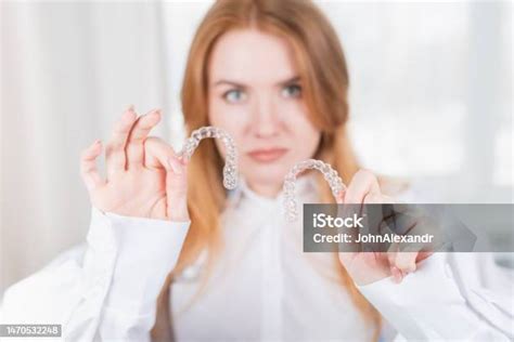 치과 치료 치아에 교정기를 착용한 웃는 소녀는 손에 교정장치를 들고 그 차이를 보여줍니다 건강관리와 의술에 대한 스톡 사진 및