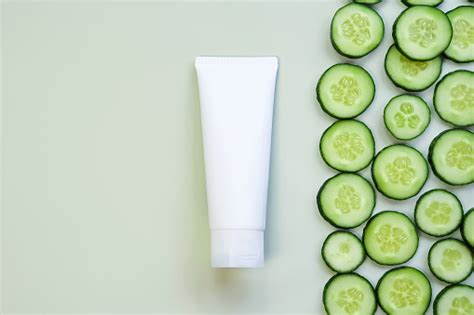모형 흰색 짜기 병 화장품 튜브와 녹색 배경에 신선한 얇게 썬 오이 바디 크림 젤 스킨 케어 자외선 차단제 보습제 치약 전면