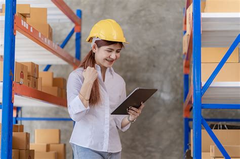 한 아시아 여성이 작은 창고의 선반에서 소포를 확인합니다 상품을 배달하기위한 물류 서비스를위한 온라인 상점 바코드를 발송하기 전에 확인하십시오 건네주기에 대한 스톡 사진 및