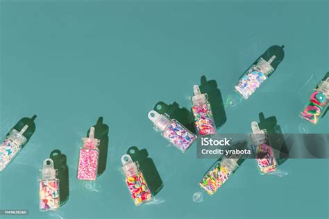 청록색 배경에 유리 항아리에 네일 아트와 메이크업을 위한 구색 컬러 반짝이 트렌드 플랫은 Sahdows와 눈부심이 있는 병에 손톱을 위한 반짝이로 누워 있으며 매니큐어