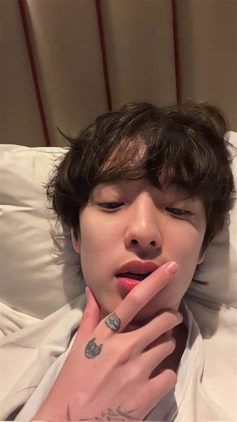 A Young Man Laying In Bed With His Hand On His Face And Fingers Under