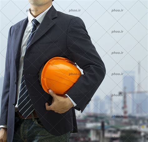 عکس مهندس با کت شلوار و کلاه ایمنی در پس زمینه شهر عکس با کیفیت و تصاویر استوک حرفه ای