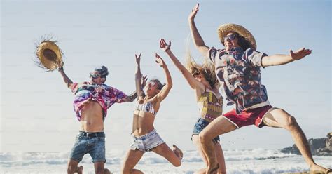 행복과 젊은 세대는 여름 휴가 휴가를 위해 해변에서 우정을 쌓으며 함께 즐거운 시간을 보내고 푸른 바다와 하늘을 배경으로 많이