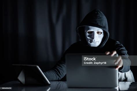 미스터리 남자 까마귀 해커 노트북 컴퓨터 보고 흰색 마스크를 착용 익명 사회 마스킹입니다 랜 섬 사이버 공격 또는 인터넷 보안