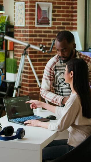 Vertical Interracial Creative Team Programing Code On A Laptop And Debugging Using Digital