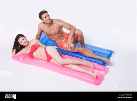 Couple In Beach Wear Lying On Their Side On A Float Each And Smiling Stock Photo Alamy
