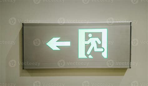 Illuminated Green Exit Sign With Running Figure And Arrow Indicating Direction Concept Related