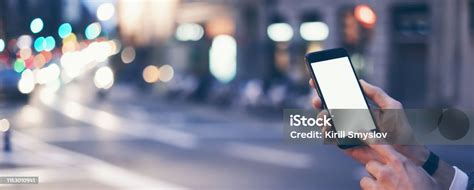 빈 화면으로 스마트폰을 들고 있는 남성 손의 근접 촬영 이미지 문자 메시지 또는 컨텐츠에 대 한 모의 광고 준비 핸드폰으로 남자의 손 빈 디스플레이 나이트 스트리트
