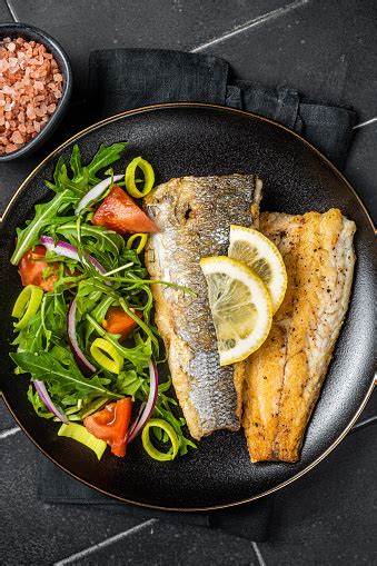 샐러드와 함께 구운 농어 필레 Branzino 생선 검은 배경입니다 상위 뷰 바다농어에 대한 스톡 사진 및 기타 이미지 바다농어 물고기 식사 음식 Istock