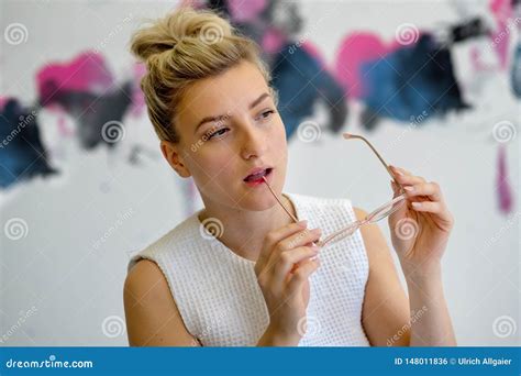 Portrait Photograph Of A Young Woman With Glasses And Blond Pinned Hair
