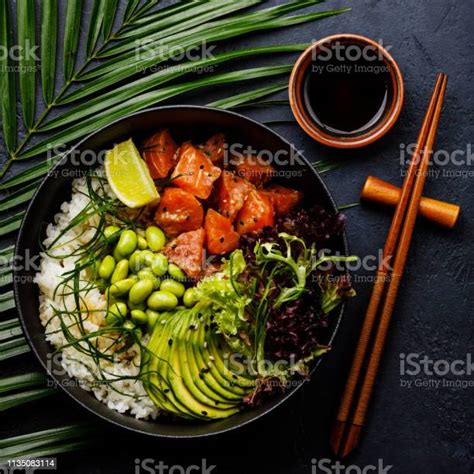 연어 찜 그릇 생 생선 샐러드 아시안 트 렌 디 한 음식 간장 콩 쌀 아보카도와 양상추 열 대 잎과 어두운 배경에 그릇에 0명에