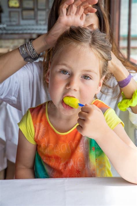 Una NiÃ±ita Linda Comiendo Helado Y Mirando Sentada En Las Piernas De