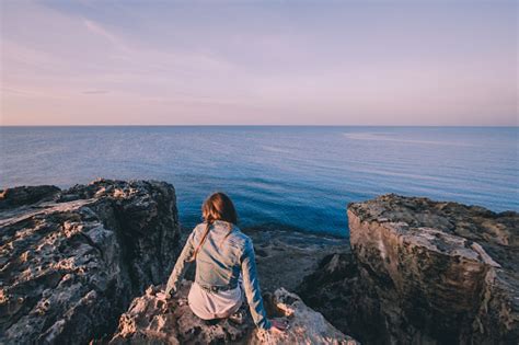 여름 산의 절벽 꼭대기에 바다 근처에 앉아 바다와 자연의 전망을 즐기는 여성 여행자 케이프 그레코 키프로스 지중해 일출 가까운에 대한 스톡 사진 및 기타 이미지 Istock