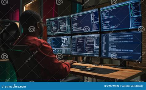 Black Cyber Security Specialist Coding On Desktop Computer With Six Monitors In Dark Office
