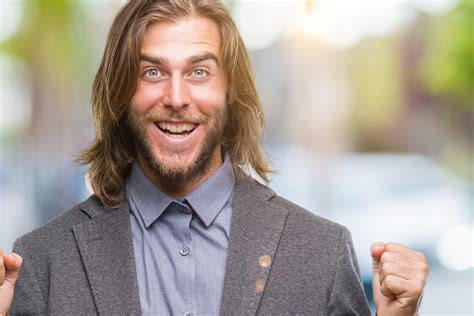 축 하 하는 고립 된 배경 위에 긴 머리를 가진 젊은 잘생긴 사업가 놀라게 무기 제기와 성공을 위한 깜짝 놀라게 고 눈을 엽니다