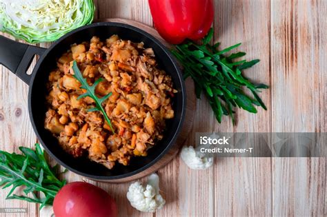 야채 감자 양파 당근 콜리플라워 토마토 소스를 곁들인 후추 마늘 허브를 나무 테이블에 튀긴 요리로 곁들인 소고기 부르기뇽 스튜 나무 배경에 소박한 평면 누워 공간을