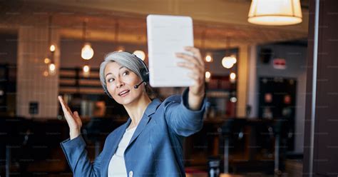 전자 패드 Pc를 들고 화상 통화를 통해 동료와 이야기하는 동안 헤드셋을 착용한 매력적인 사업가 사진 Unsplash의 사진술 이미지