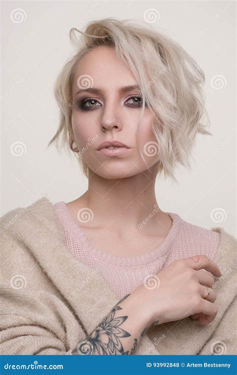 Портрет девушки блондинкы с составом темного глаза и короткими волосами в свете розовым