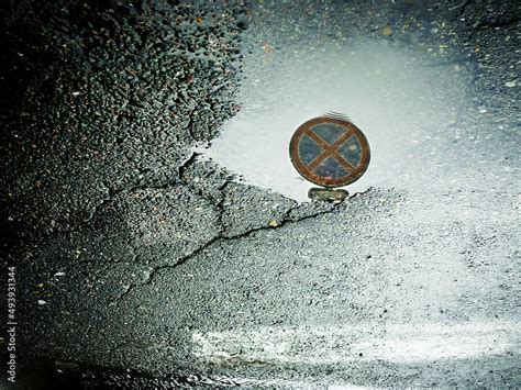 Road Sign Reflected On Water Surface Wet Cracked Asphalt Background